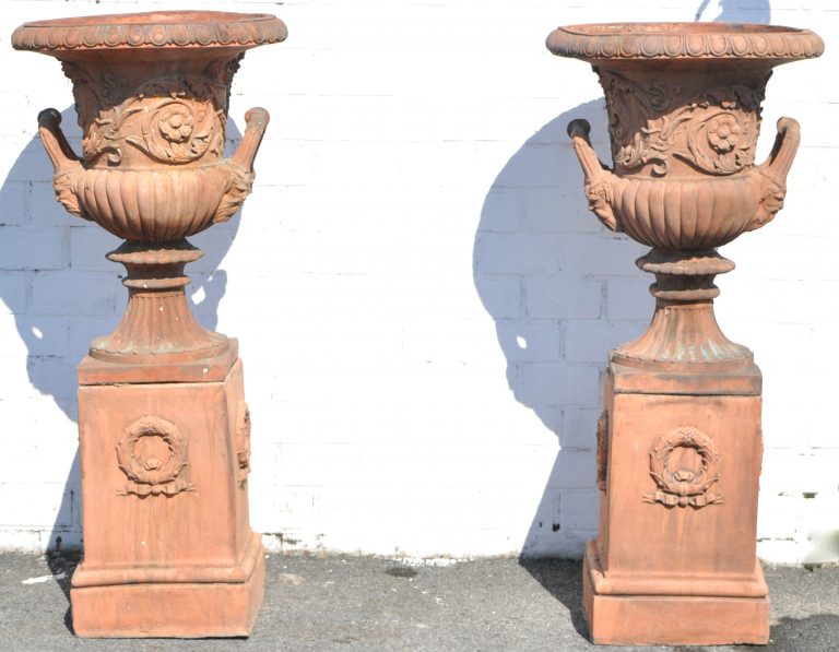 Een paar rijk gedecoreerde terracotta tuinvazen op sokkel. – Jordaens N.V. Veilinghuis
