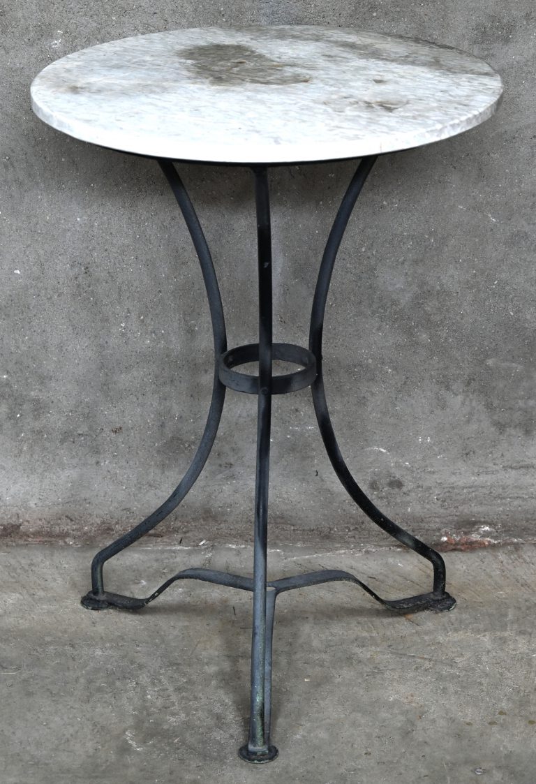 Een ronde ijzeren tuintafel met marmeren blad. Het tafelblad is ...