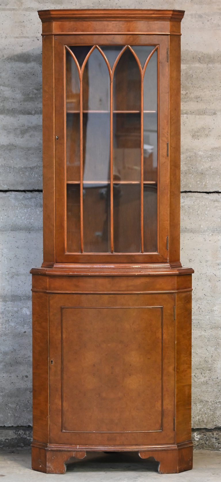 Een notenhouten hoekvitrine met schuine hoeken en licht gebogen front ...